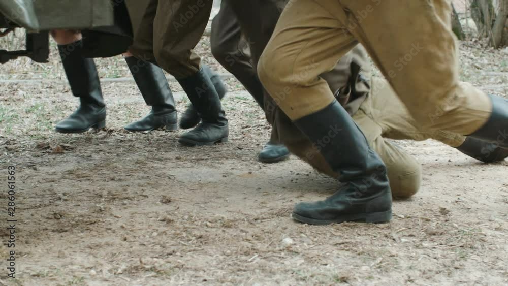 Close-up of boot soldiers in the form of world war II pushing a stalled ...