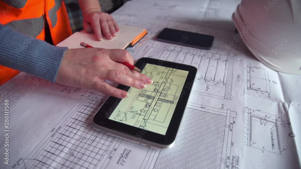 Woman architect uses tablet examining blueprints Stock Video | Adobe Stock