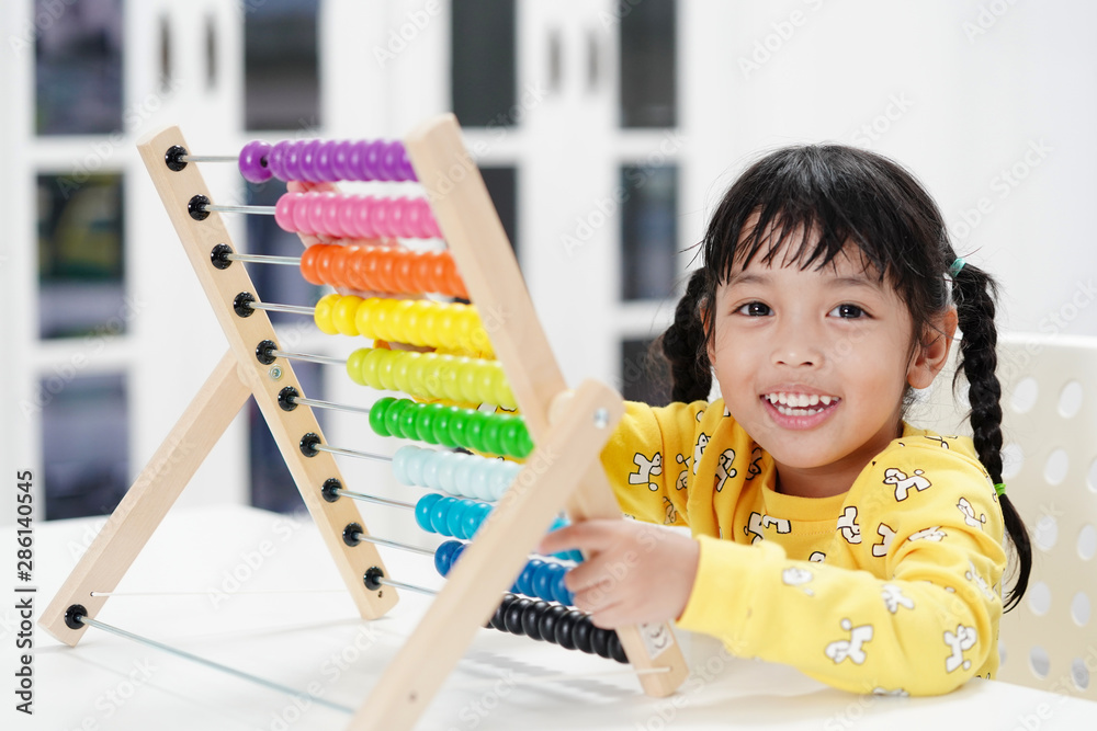 Cute Asian little kid girl playing with abacus at home. Smart child learning to count. learning ...