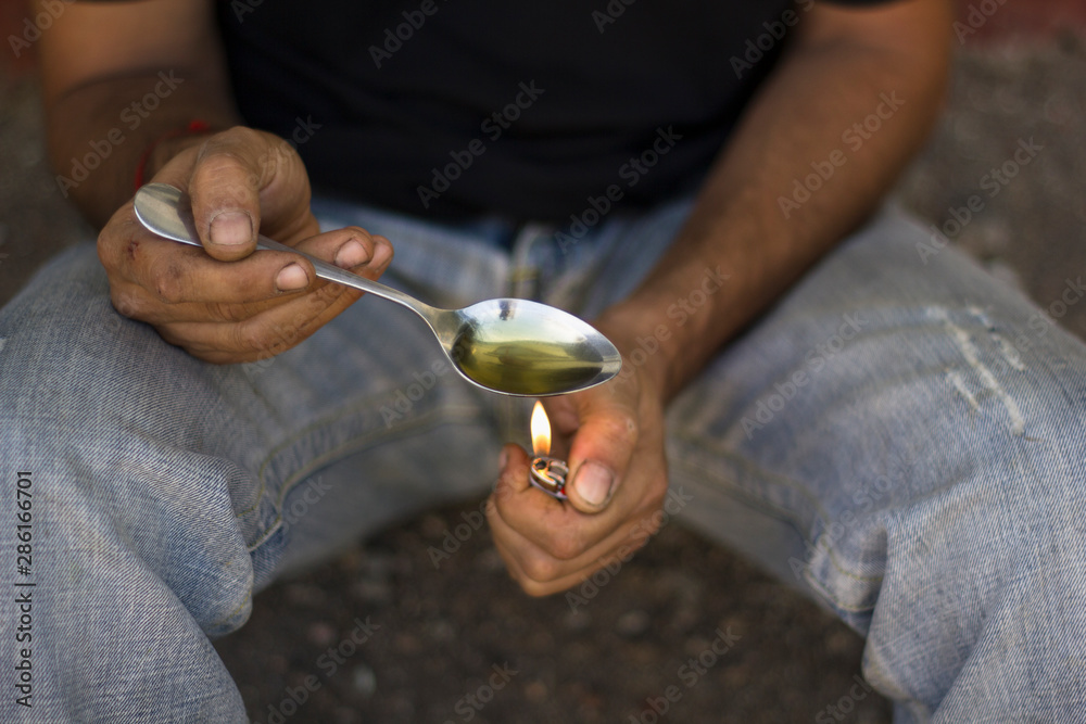 Drug addicted man sitting on the ground with drugs in hands. Anti ...