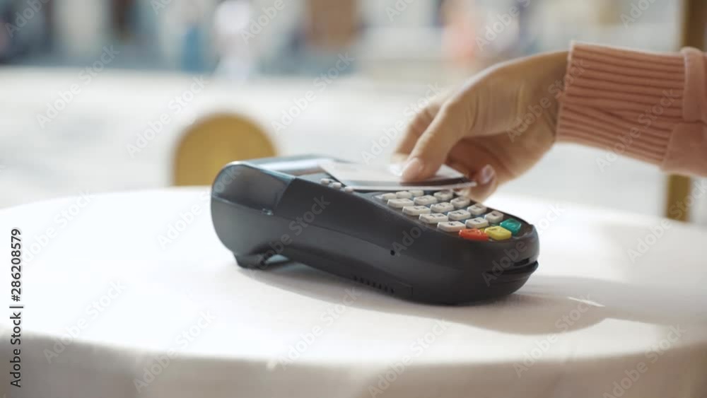 Young woman applying contactless credit card on pos terminal providing ...