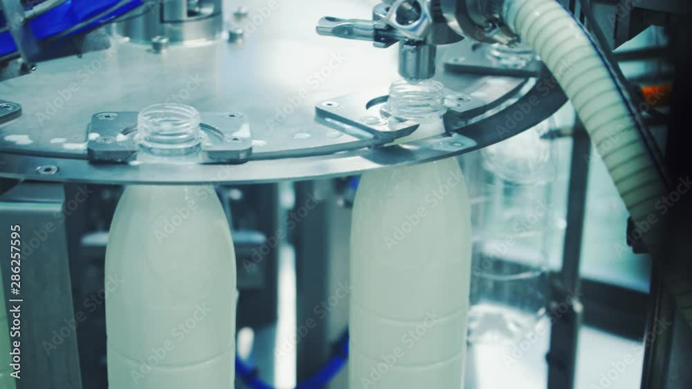 Plastic bottles filling with milk. Milk pouring into plastic bottle at ...