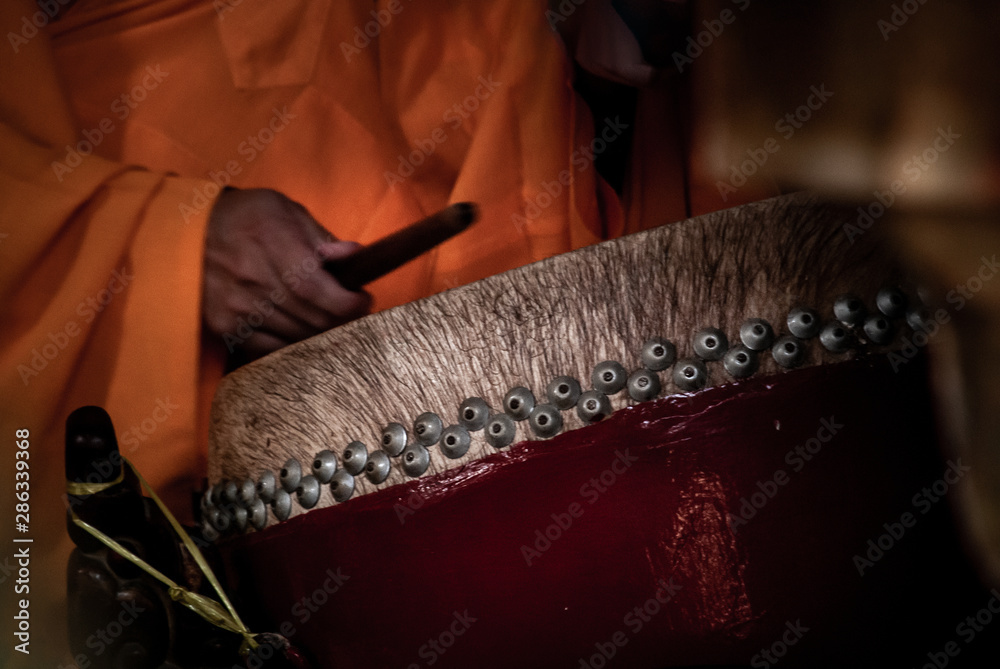 Hand of Buddhist monk striking a drum to pay respect for Buddhism pray ...