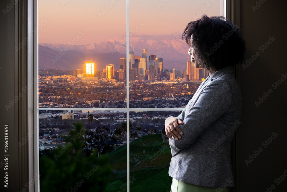 Black female business woman looking out the window of an office in Los ...
