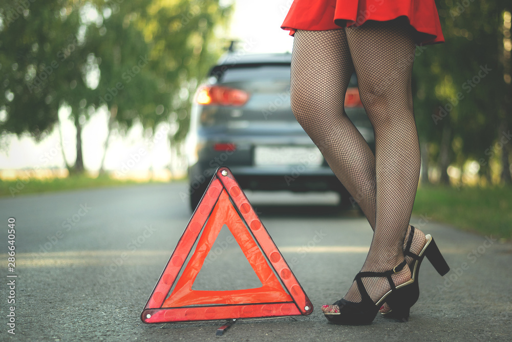 Woman legs in high heels shoes and red emergency stop sign on a broken ...