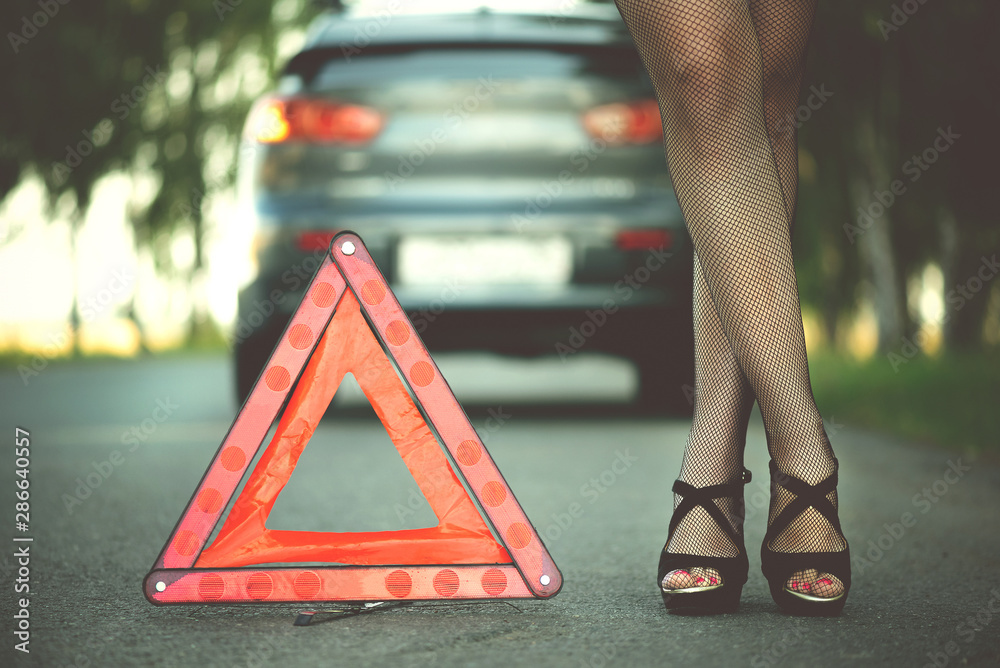 Woman legs in high heels shoes and red emergency stop sign on a broken ...
