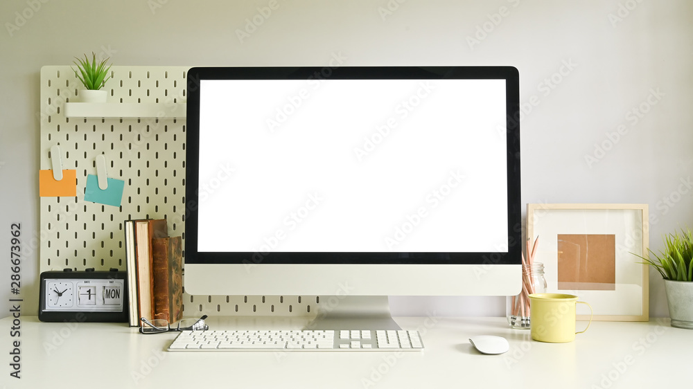 Computer empty screen on creative workspace with peg board and office ...