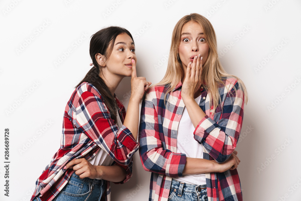 Shocked young girls friends sisters posing isolated over white wall ...