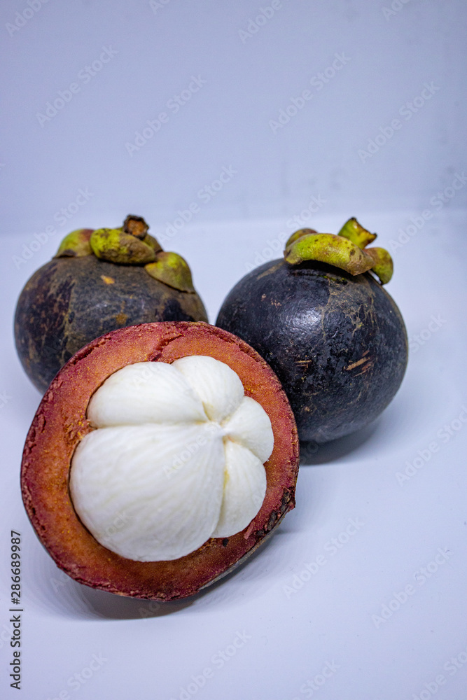 Group of mangosteen fruits cut open in half showing the white flesh and ...