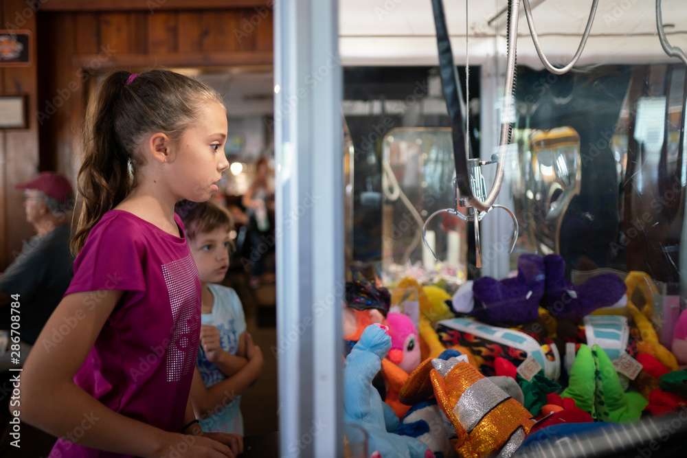 Girls Play Crane Game in an Arcade Stock Photo | Adobe Stock