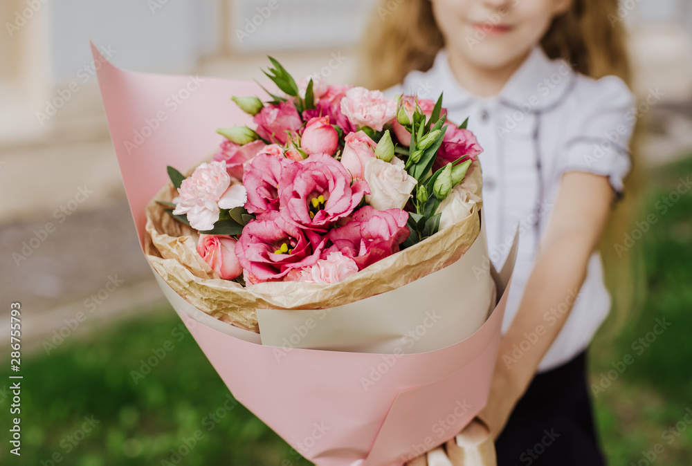 School girl dressed in school uniform holding a bright pink festive ...