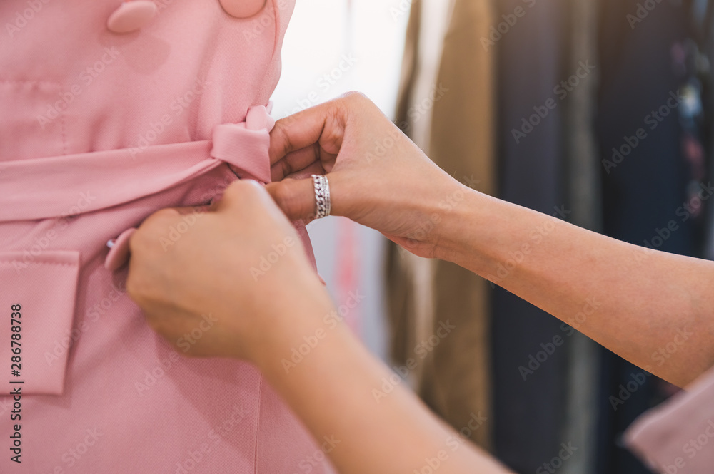 Closeup of female fashion designer girl hand making fit on formal dress ...