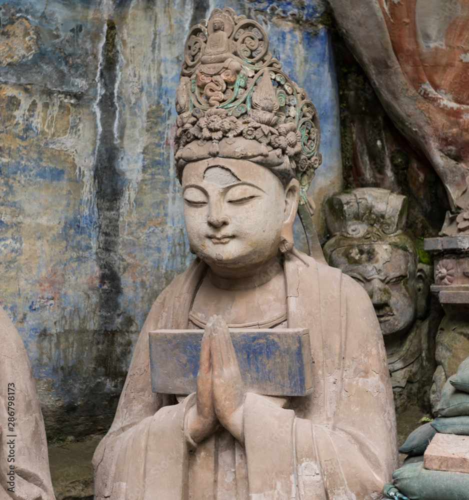 Statue of disciple or follower in front of giant Buddha at Dazu Rock ...