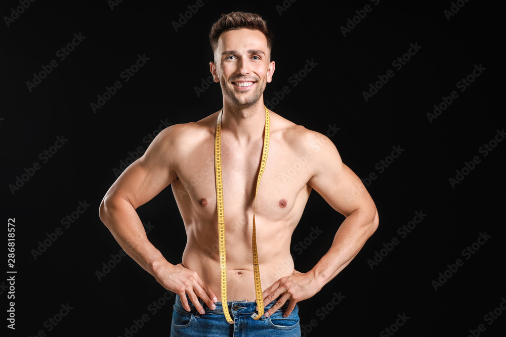 Handsome muscular man with measuring tape on dark background. Weight ...