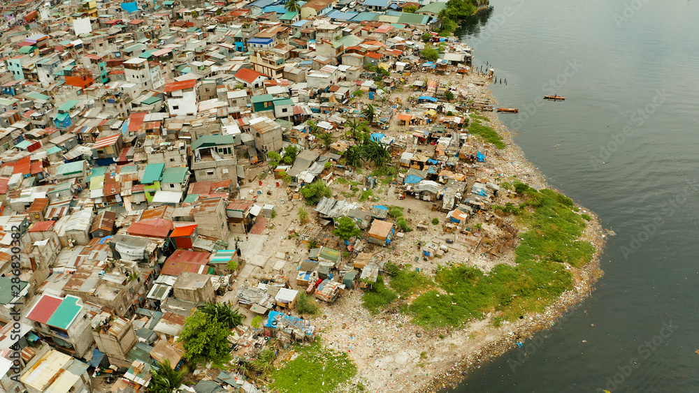 Slums in Manila on the bank of a river polluted with garbage, aerial ...