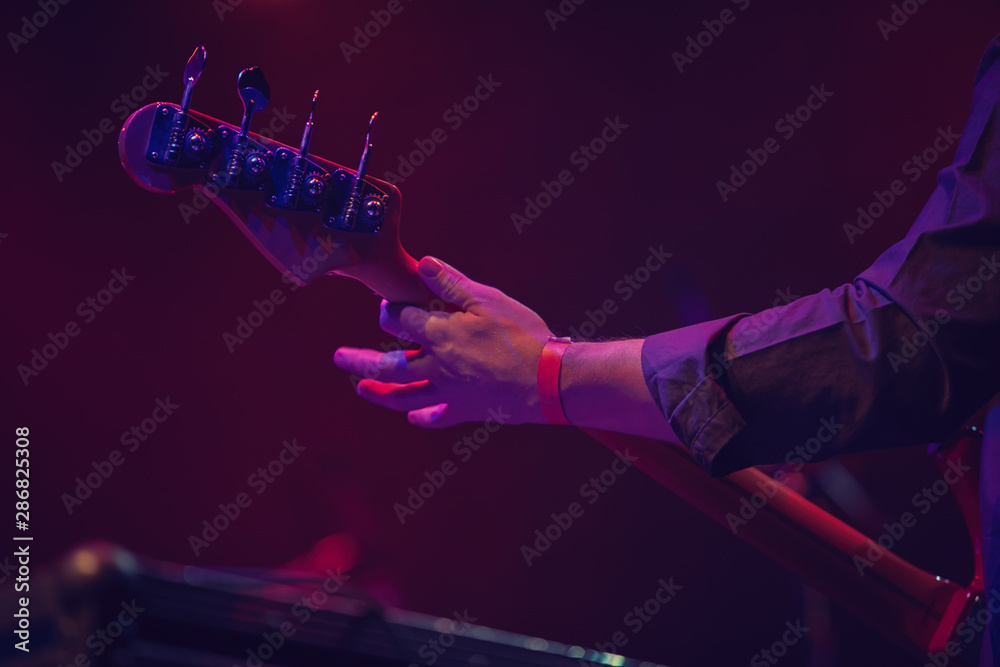 Bass guitarist playing solo part on rock concert stage in music hall ...
