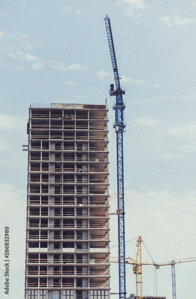 three building cranes at the background of a multi-storey building ...