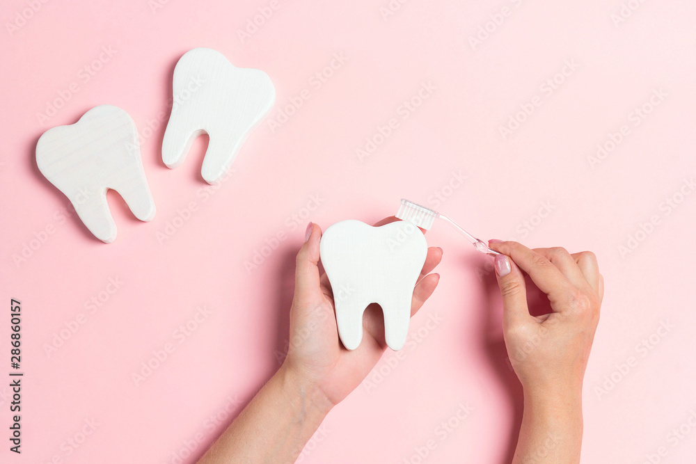 Female hands with tooth symbol and toothbrush on pink background ...