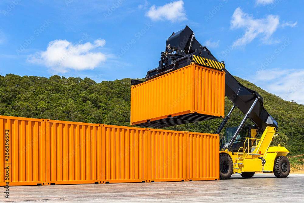 Reach stacker yellow forklift truck handling shipping container in ...