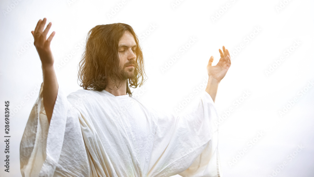Jesus raising hands illuminated with light, resurrection and ascension ...