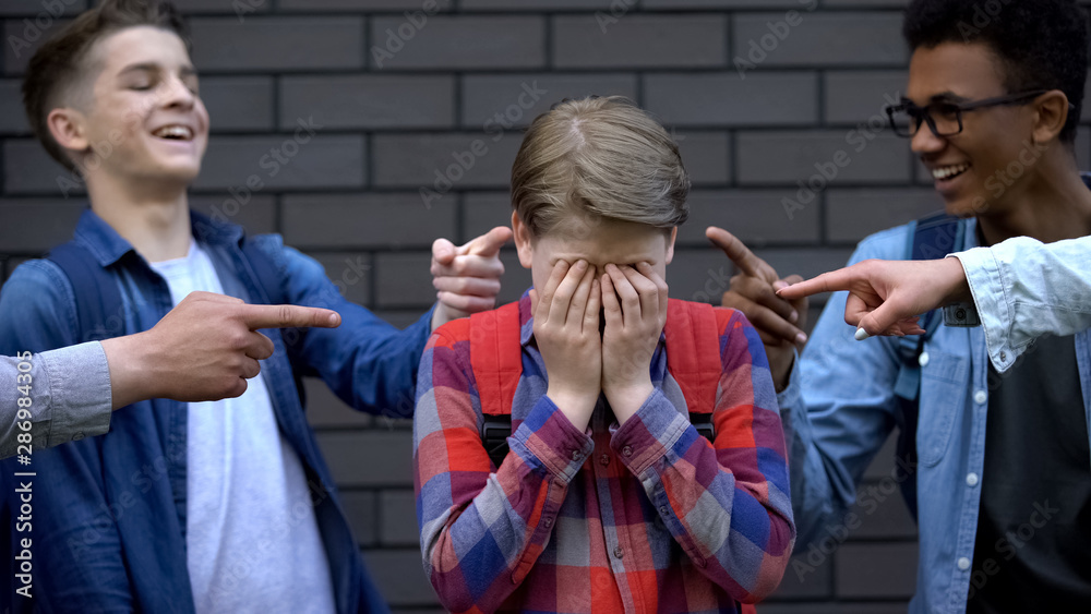 Malicious teenagers pointing fingers at boy crying, depressed victim of ...