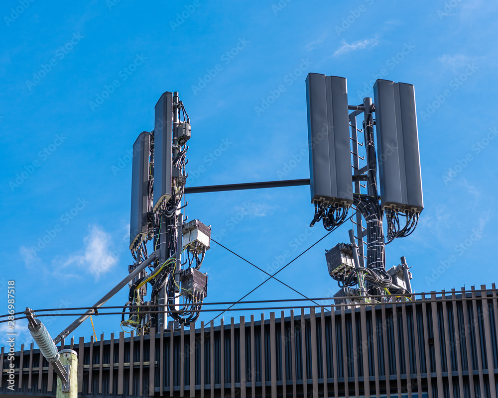 A mobile phone tower on a roof with a multiple wires and connections ...