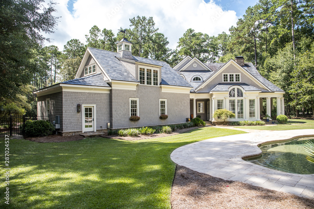 Rear view and backyard of large cape cod style home with columns and ...