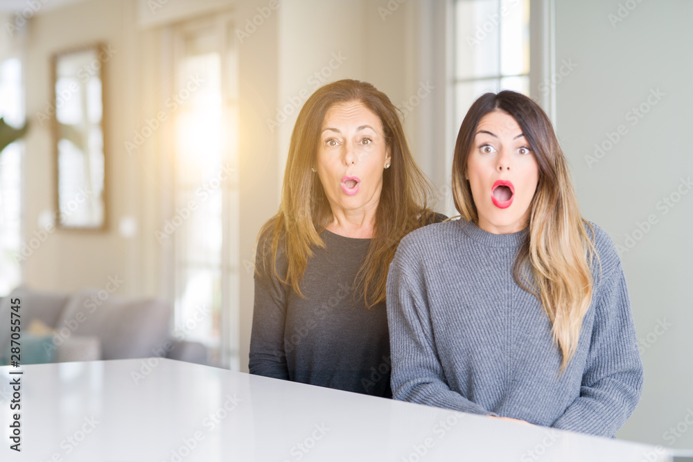 Beautiful family of mother and daughter together at home afraid and ...