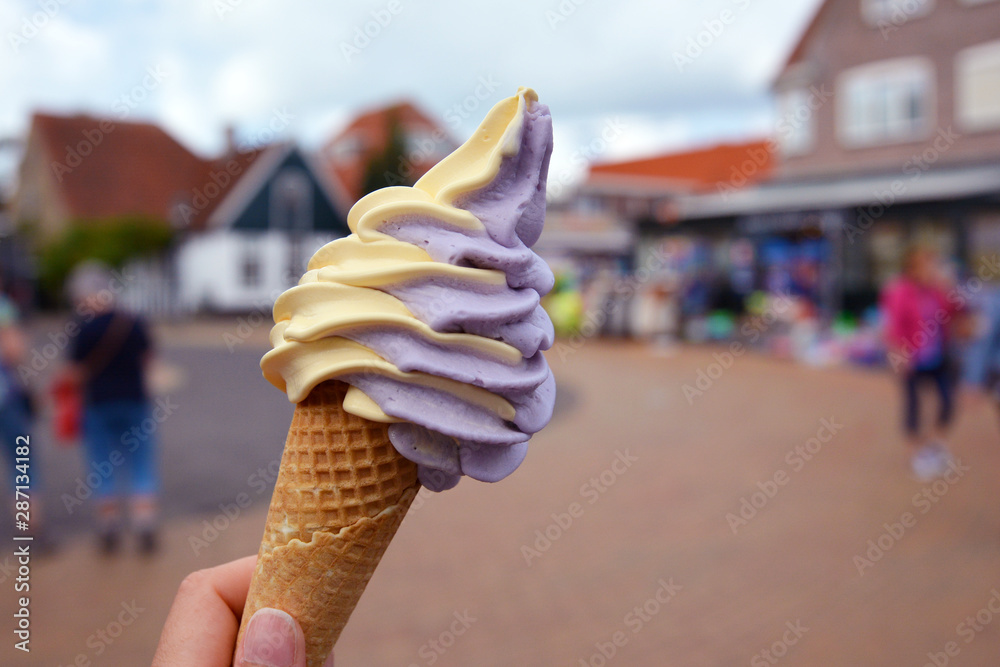 Close up of hand holding cone with mixed yellow and purple mango and ...