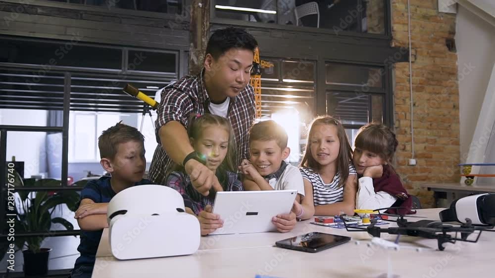 Vidéo Stock Primary school teacher at desk working with five young ...