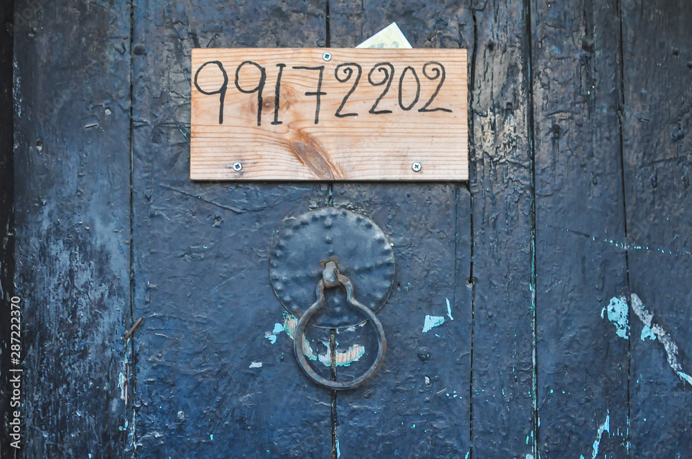 Old wooden door with a number under a door knob. Texture background ...