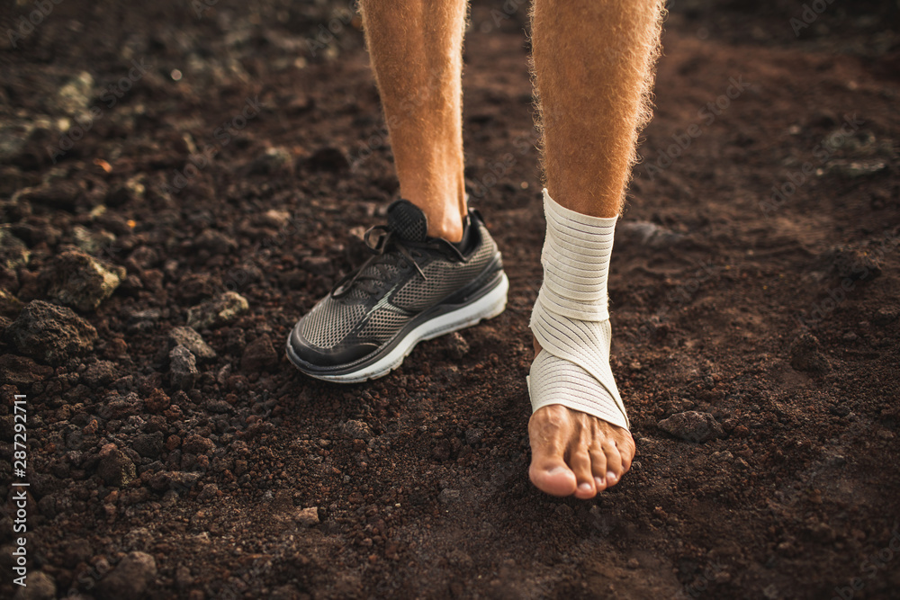 Man's ankle in compression bandage. Leg injury while trail running ...