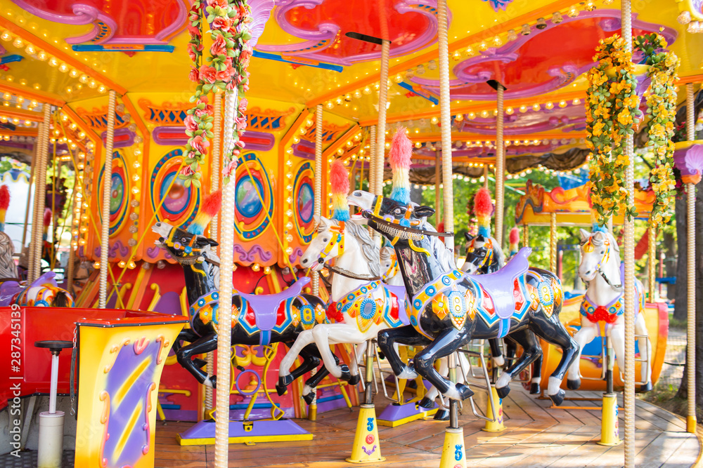 Old French carousel in a holiday park. Three horses on a traditional ...