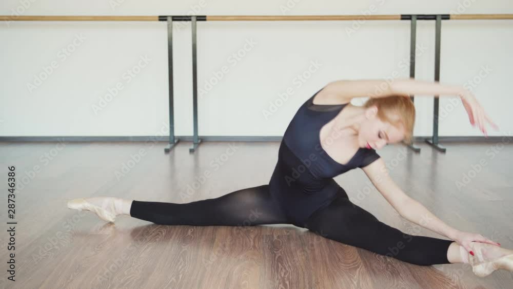 Tracking shot of graceful and flexible young ballerina in black leotard ...