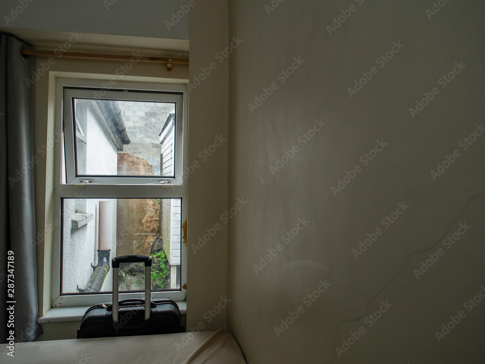 Travel case in a cheap accommodation, Small dirty window with ugly view ...