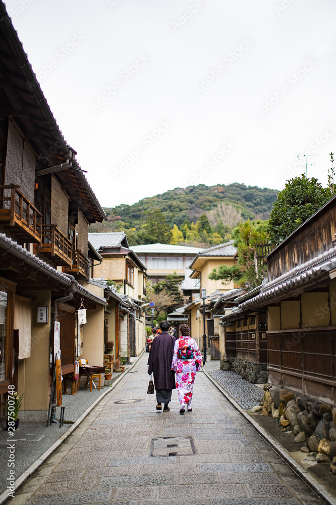 A couple dressed in the traditional Kimono are walking through the ...