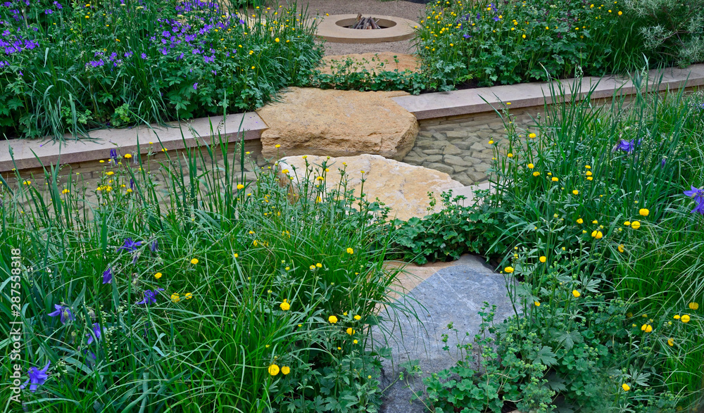 Modern water garden with flowing rill with rocks, stepping stones and ...