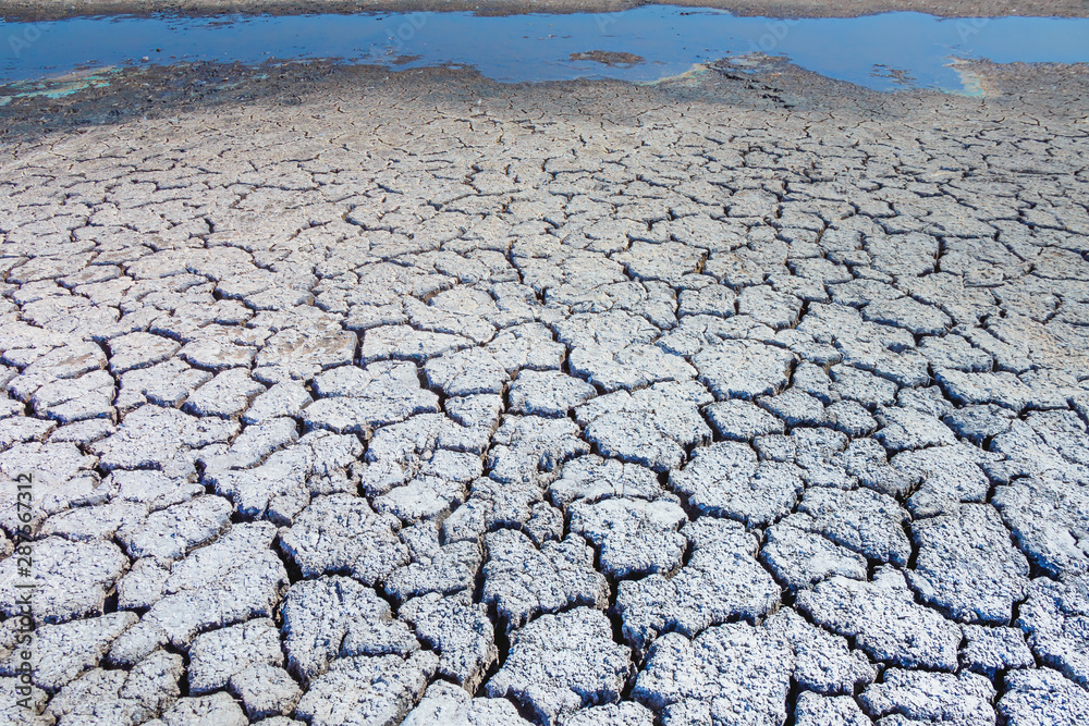 Heat, drought, disaster, saline soil, dry riverbed, blue sky reflected ...