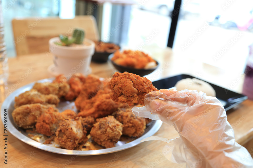 Hand in plastic glove hold spicy fried chicken ready to eat with deep ...