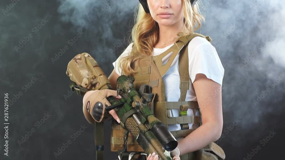 Woman soldier in military camouflage uniform protected with headphones ...