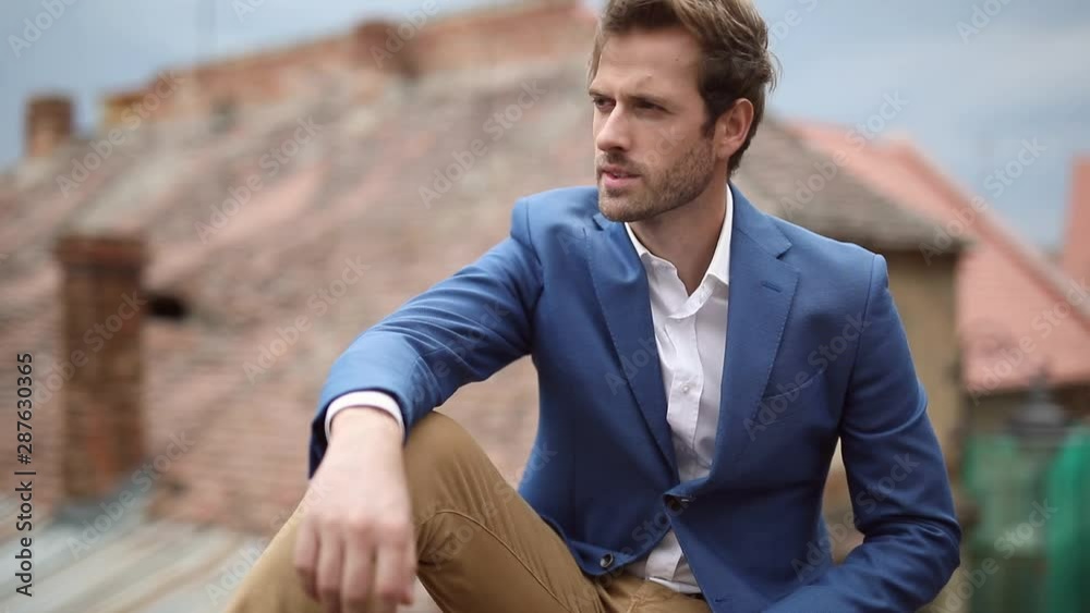 side view of a pensive seated modern man looking away and at the camera ...