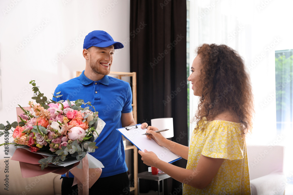 African-American woman receiving flower bouquet from delivery man ...