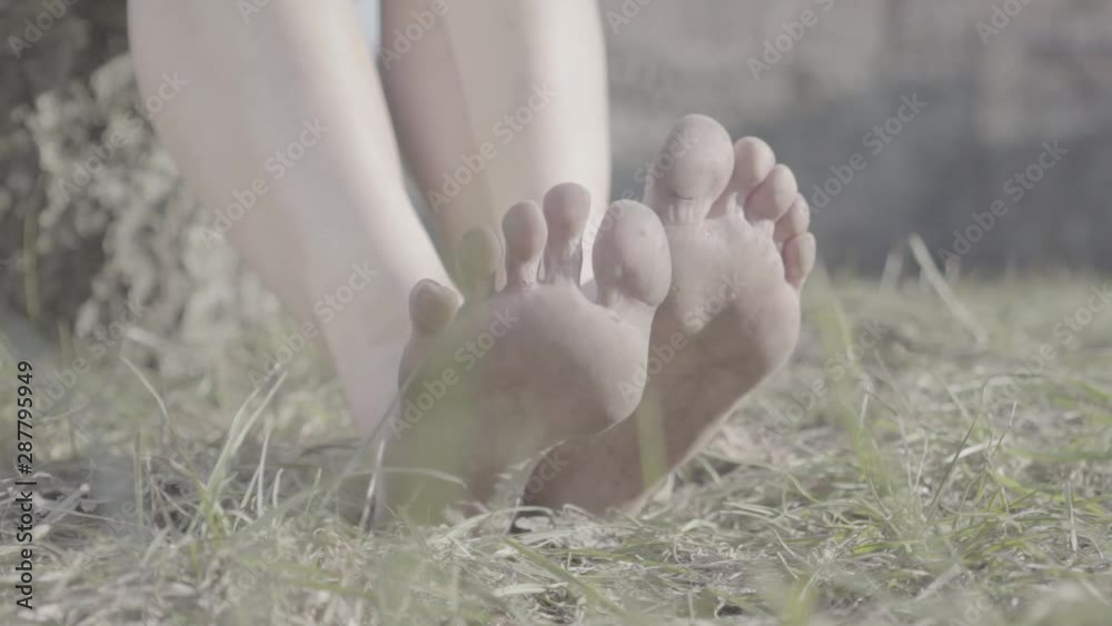 barefoot girl walks on spring grass, closeup seen legs, bright sunny ...