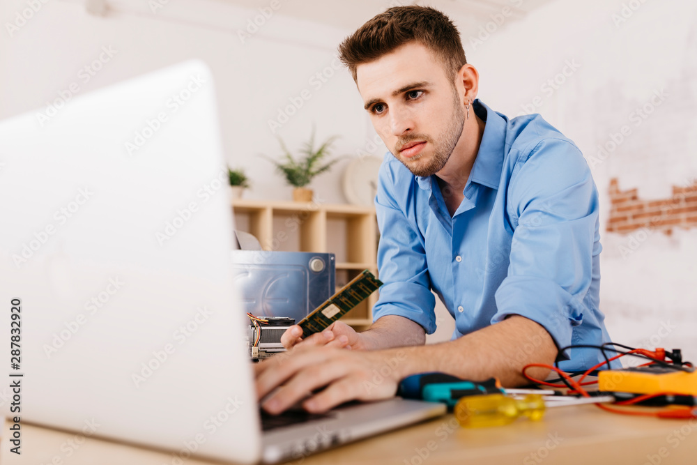 Technician repairing a desktop computer, using laptop Stock Photo ...