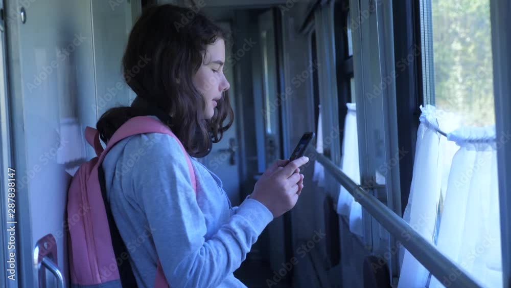 little girl walks on a train compartment car with a backpack and a ...