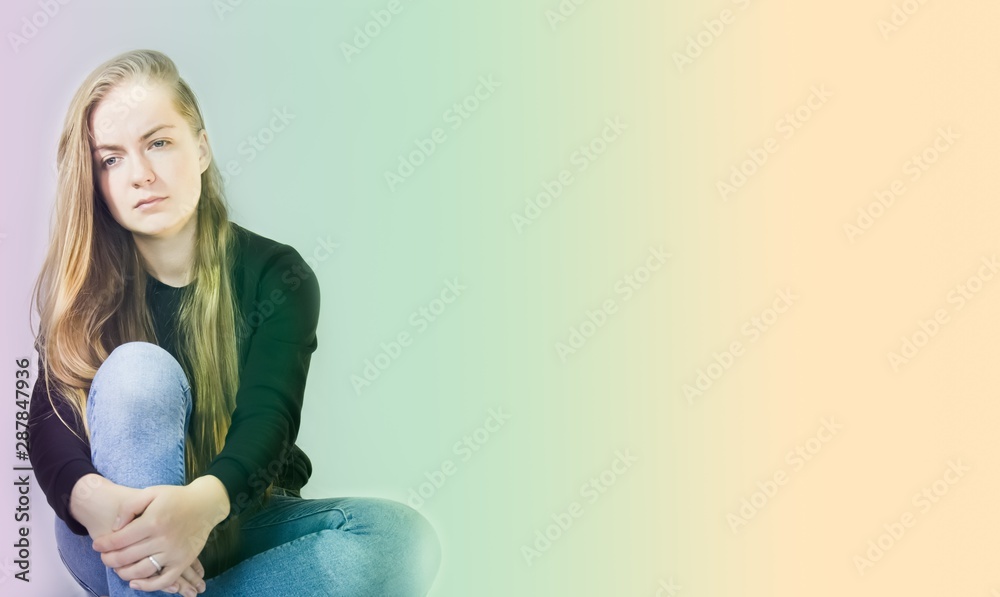 A sad girl with blond hair with in blue jeans and a black sweater in a ...