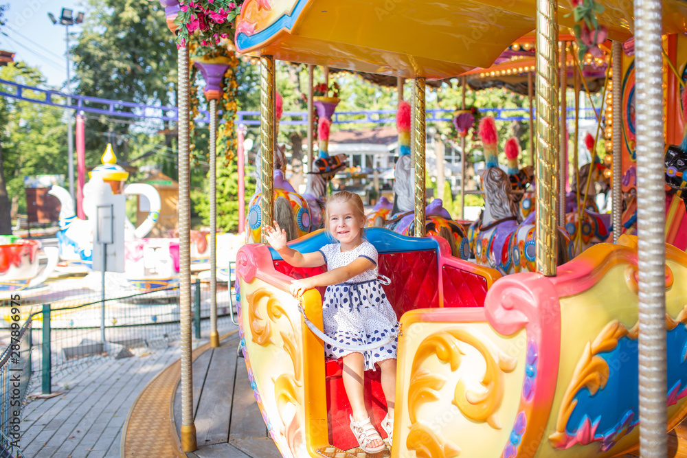 Little blonde girl on old french carousel in a holiday park. Charming ...