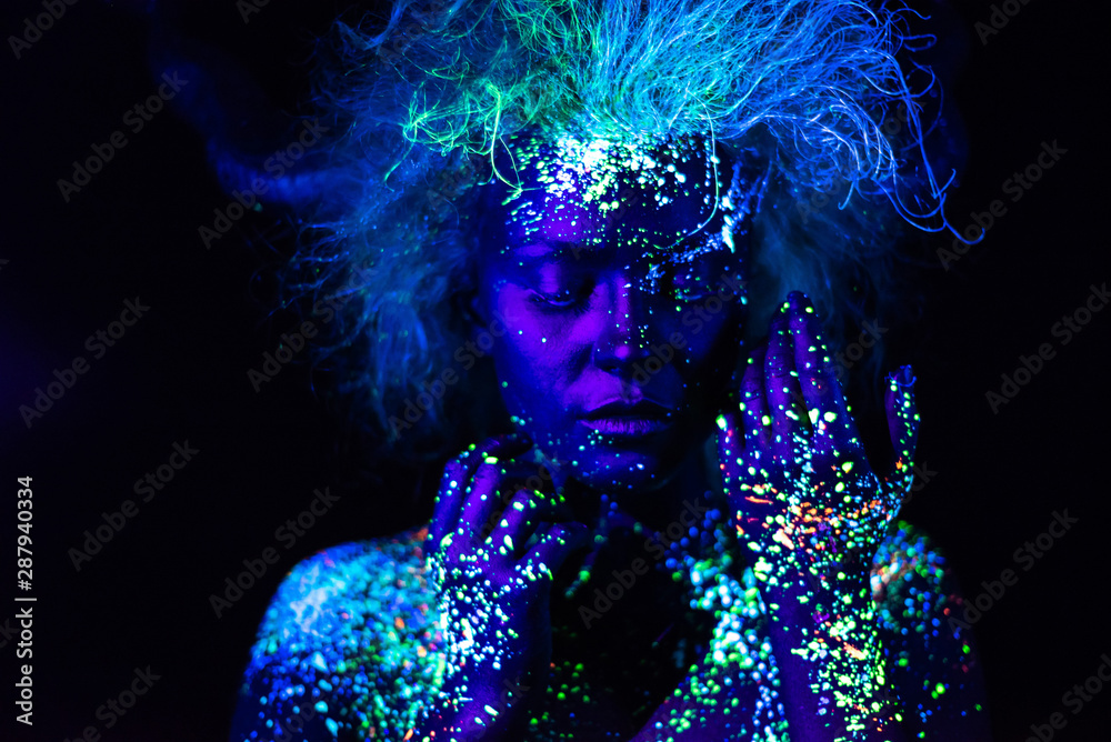 UV body art on the face of a very beautiful girl with a lush hairstyle ...
