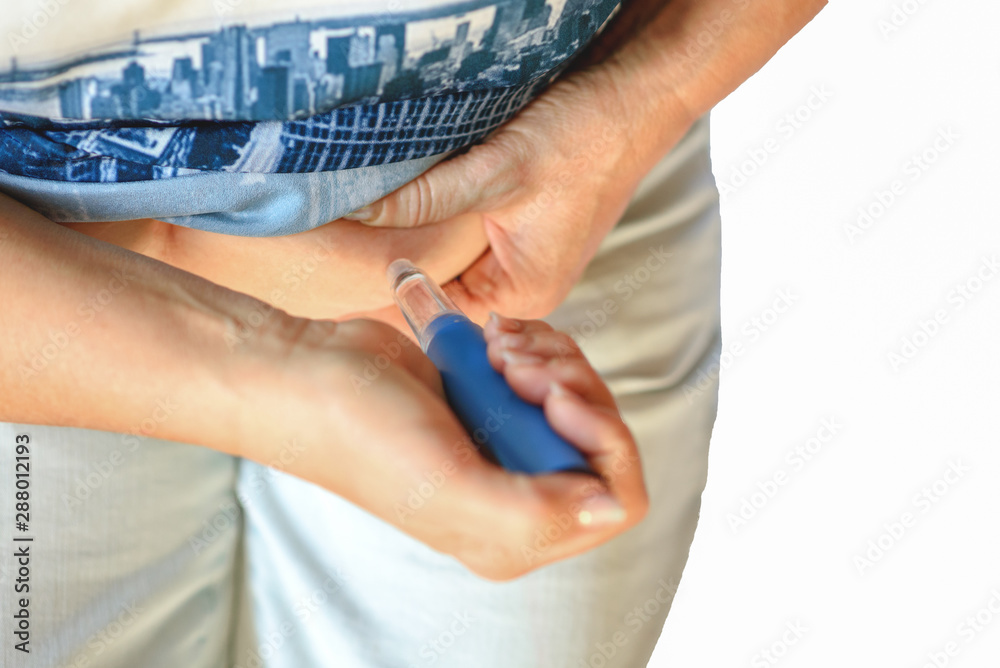 Elderly woman giving herself injection against osteoporosis in abdomen ...
