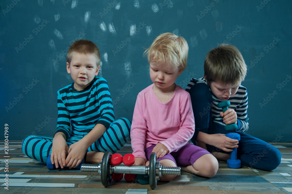 Three children are sitting on floor in room and are going to do ...